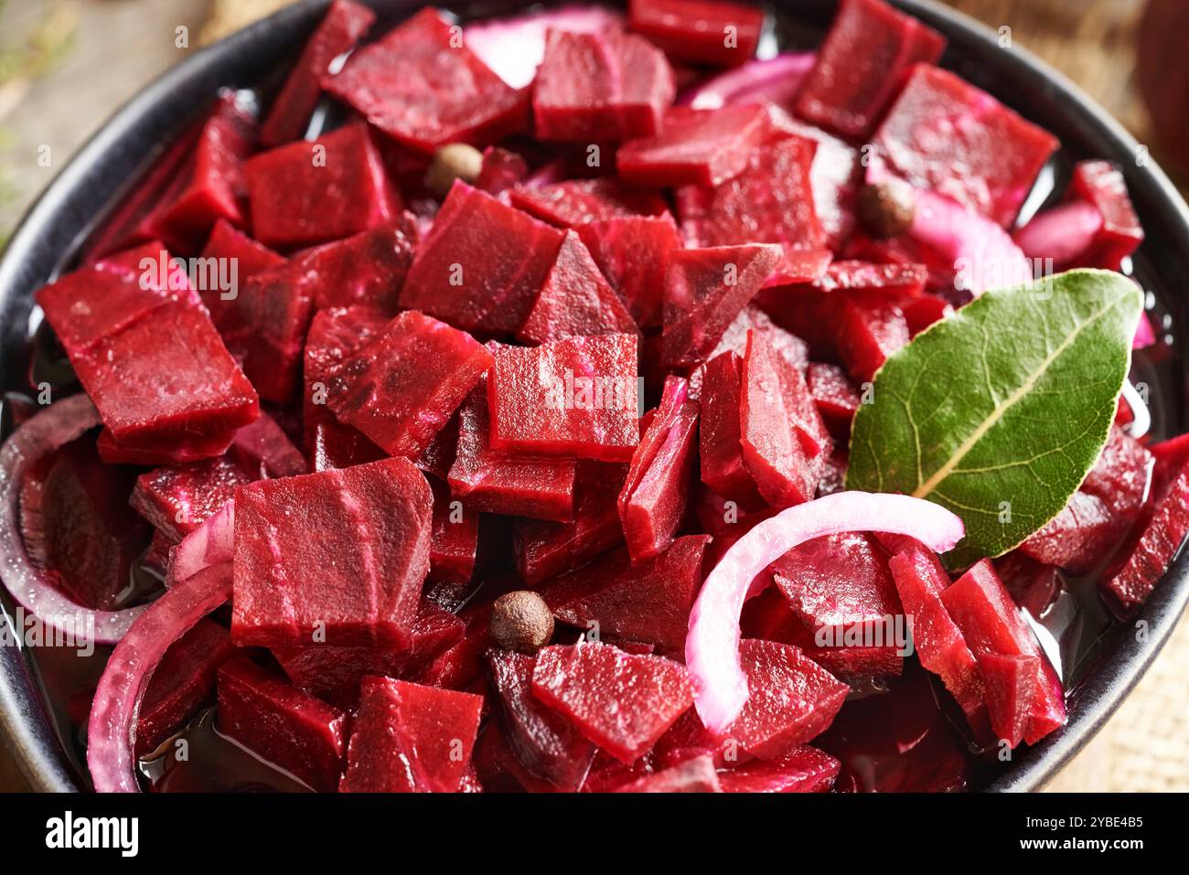 Fermented red beet kvass in a dark bowl with onions and spices, close ...