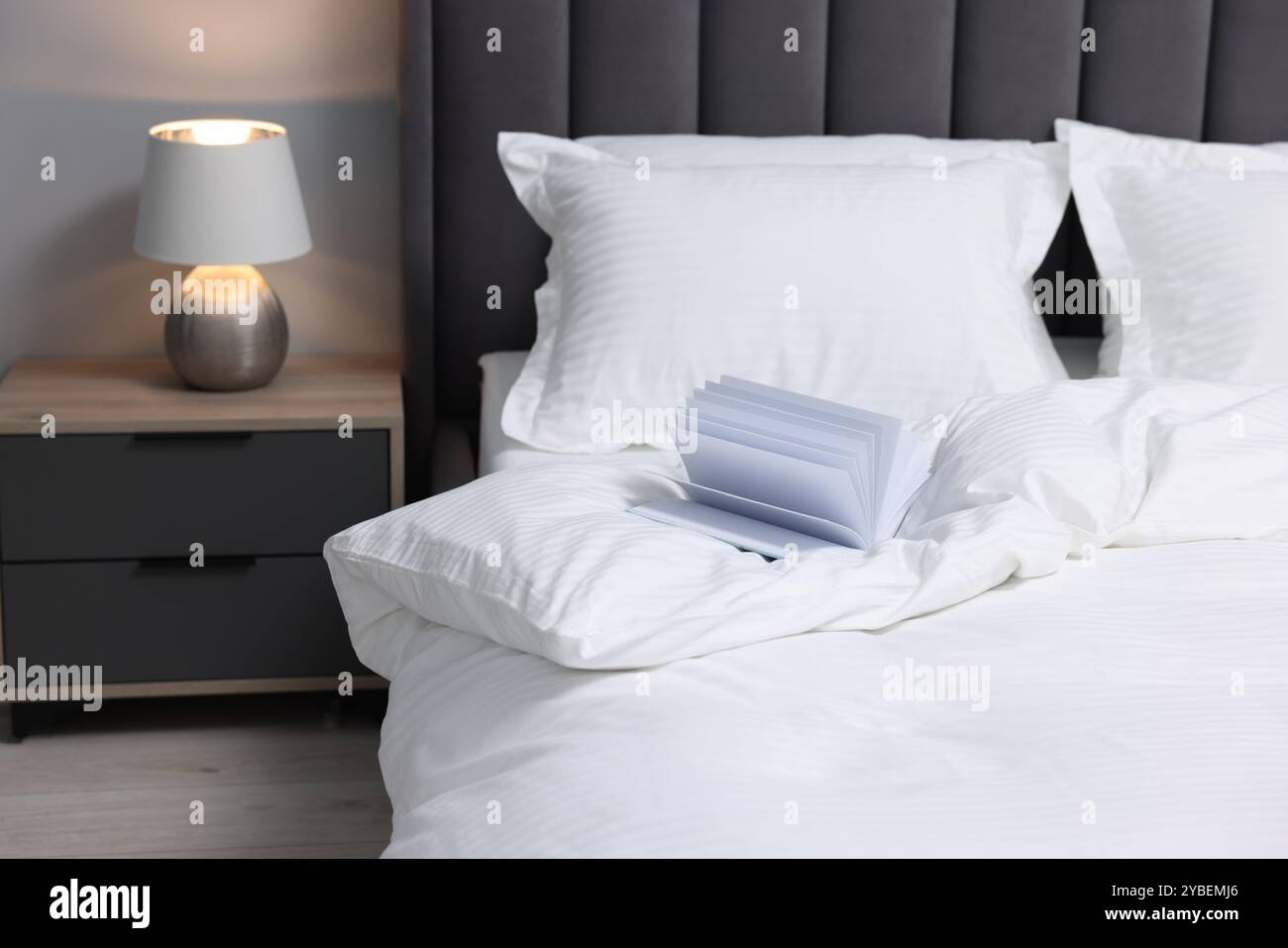 Open book on bed with clean linens indoors Stock Photo - Alamy