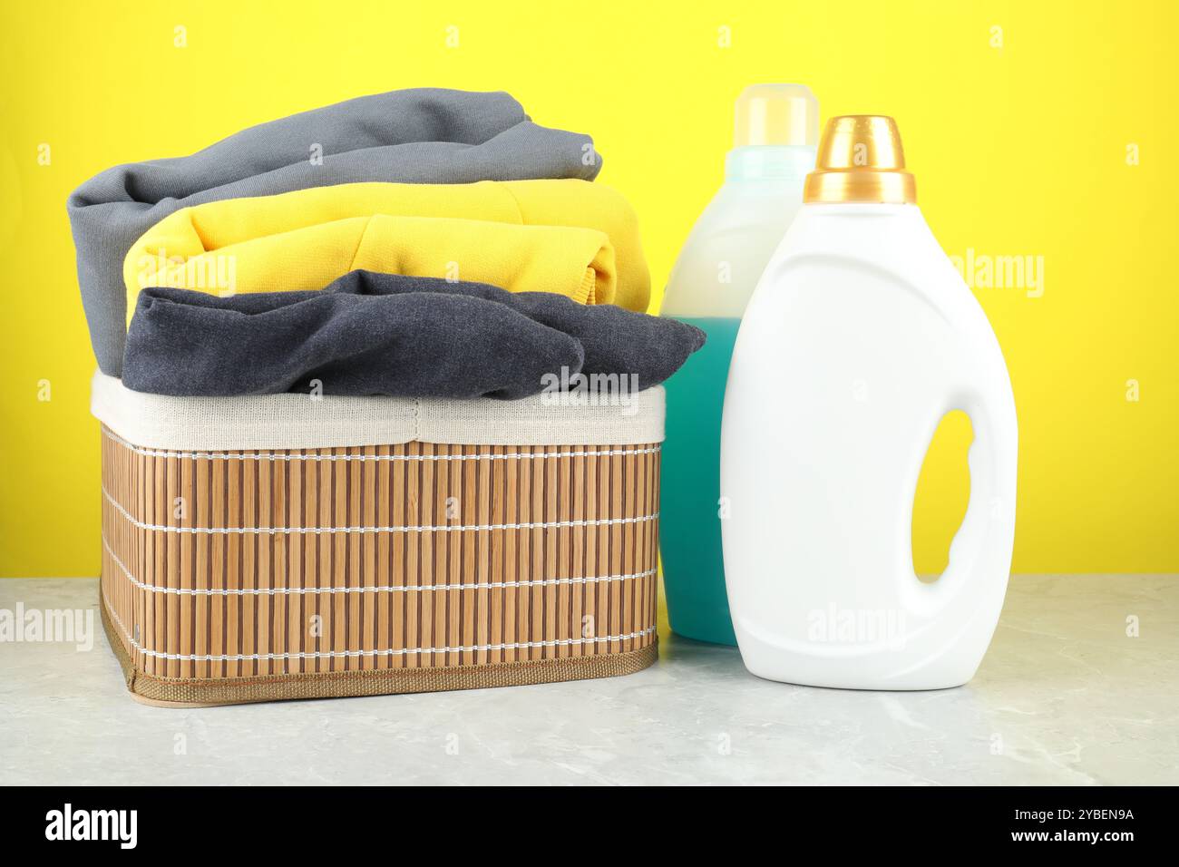 Laundry detergent in bottles and clothes on grey marble table against ...