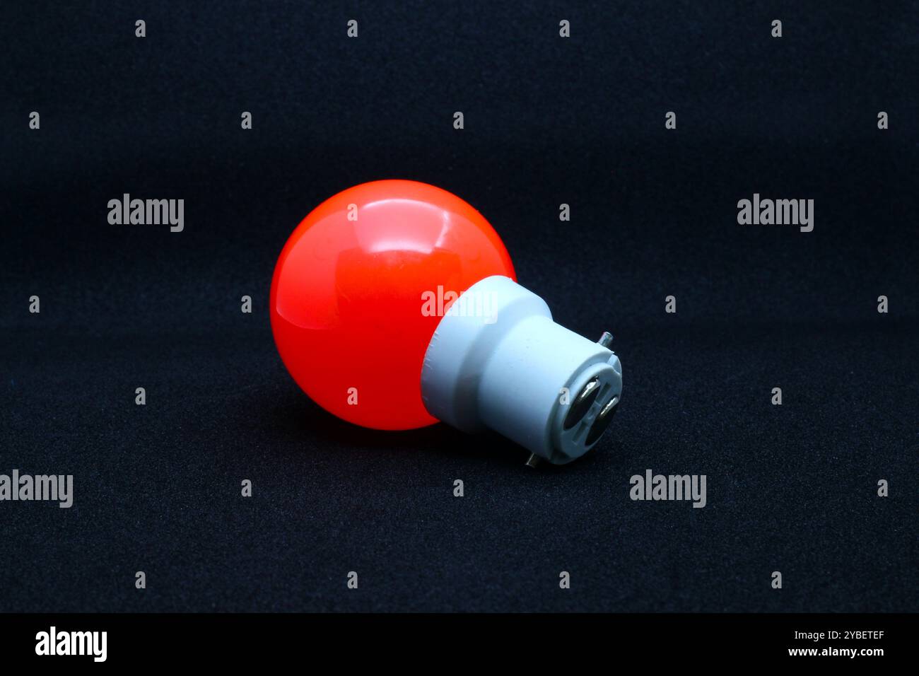 Close-up view from base of a zero watt bulb orange colored on a black ...