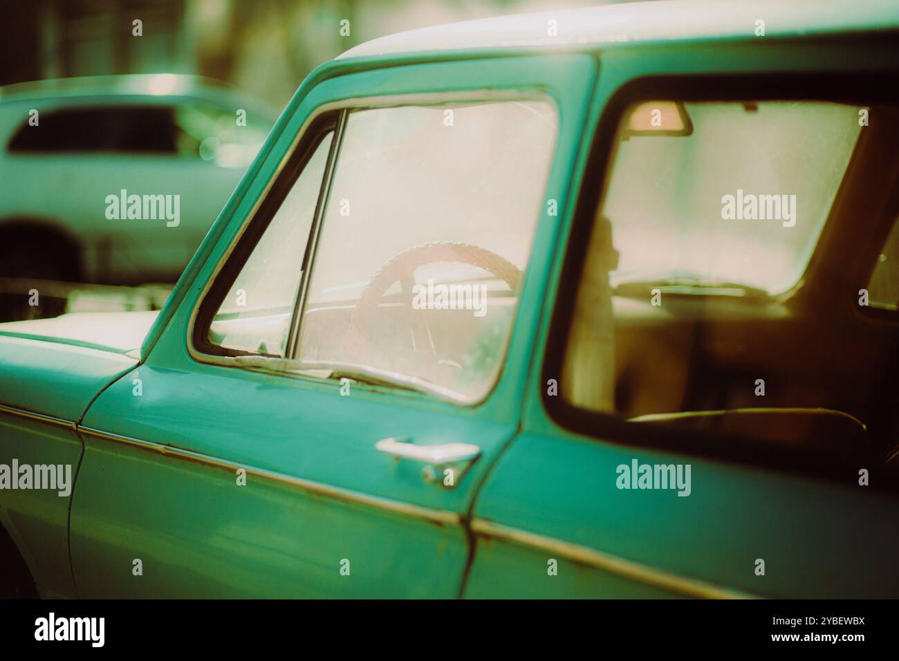 A blue retro car, with the sunlight shining through the windshield and ...