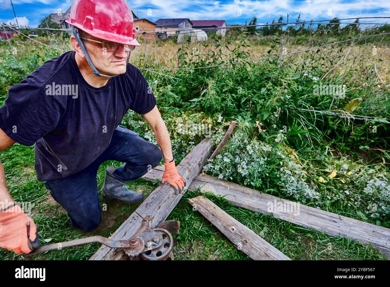 Construction worker uses manual cable winch to move load on suburban ...