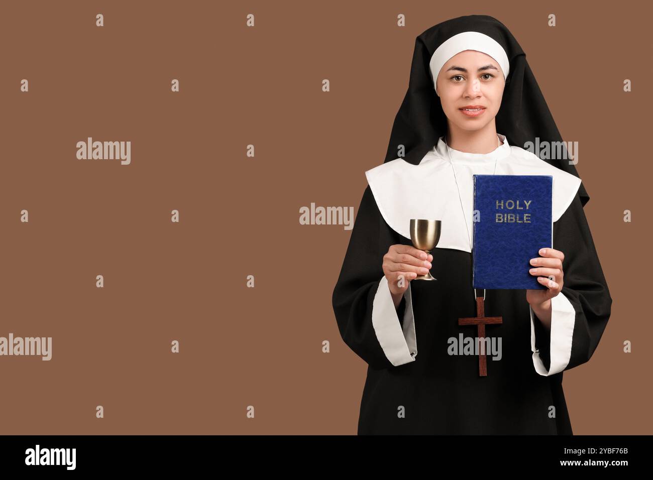 Young nun with Bible and chalice on brown background Stock Photo - Alamy