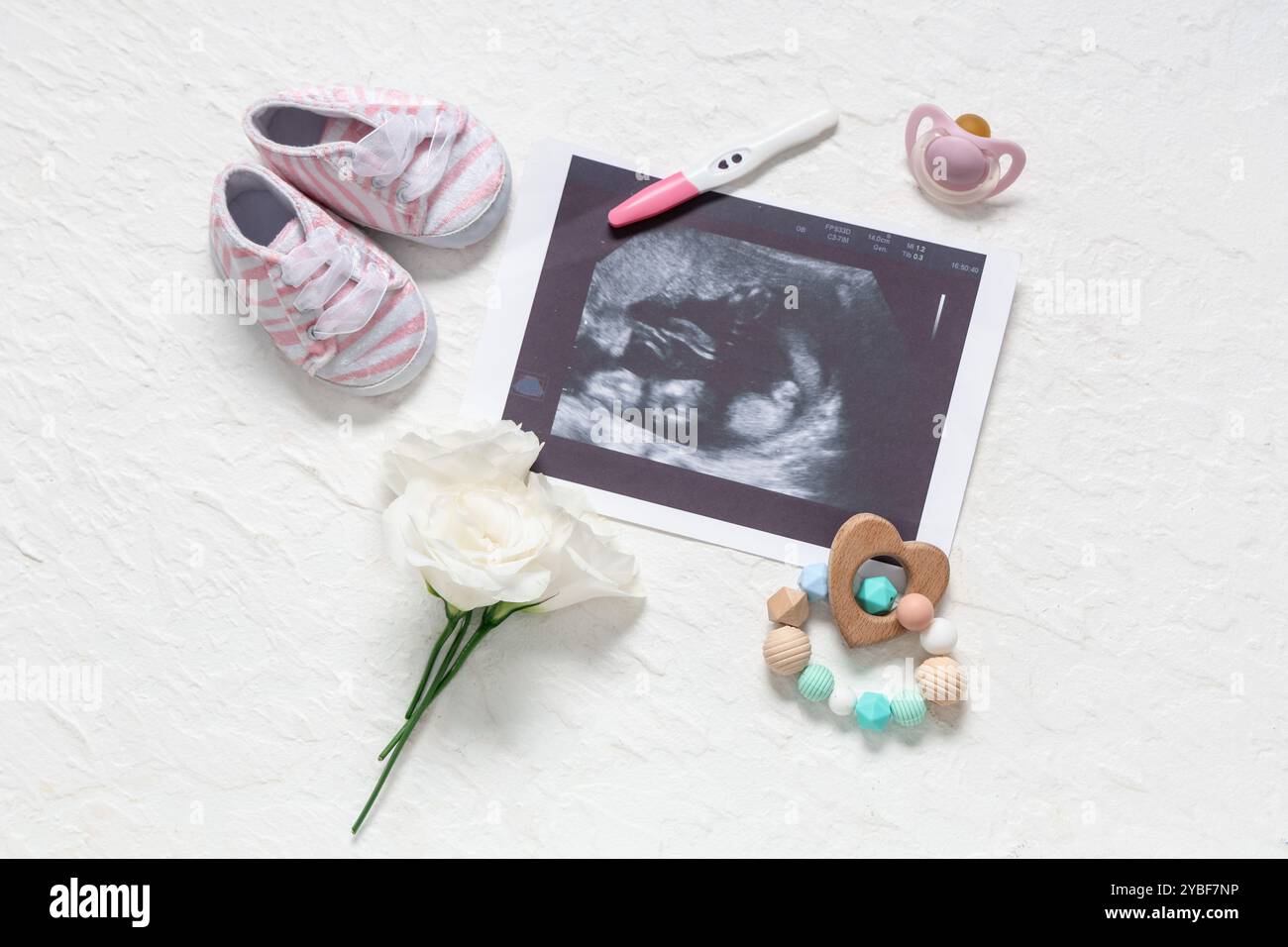 Composition with baby shoes, sonogram image, pregnancy test and toys on ...