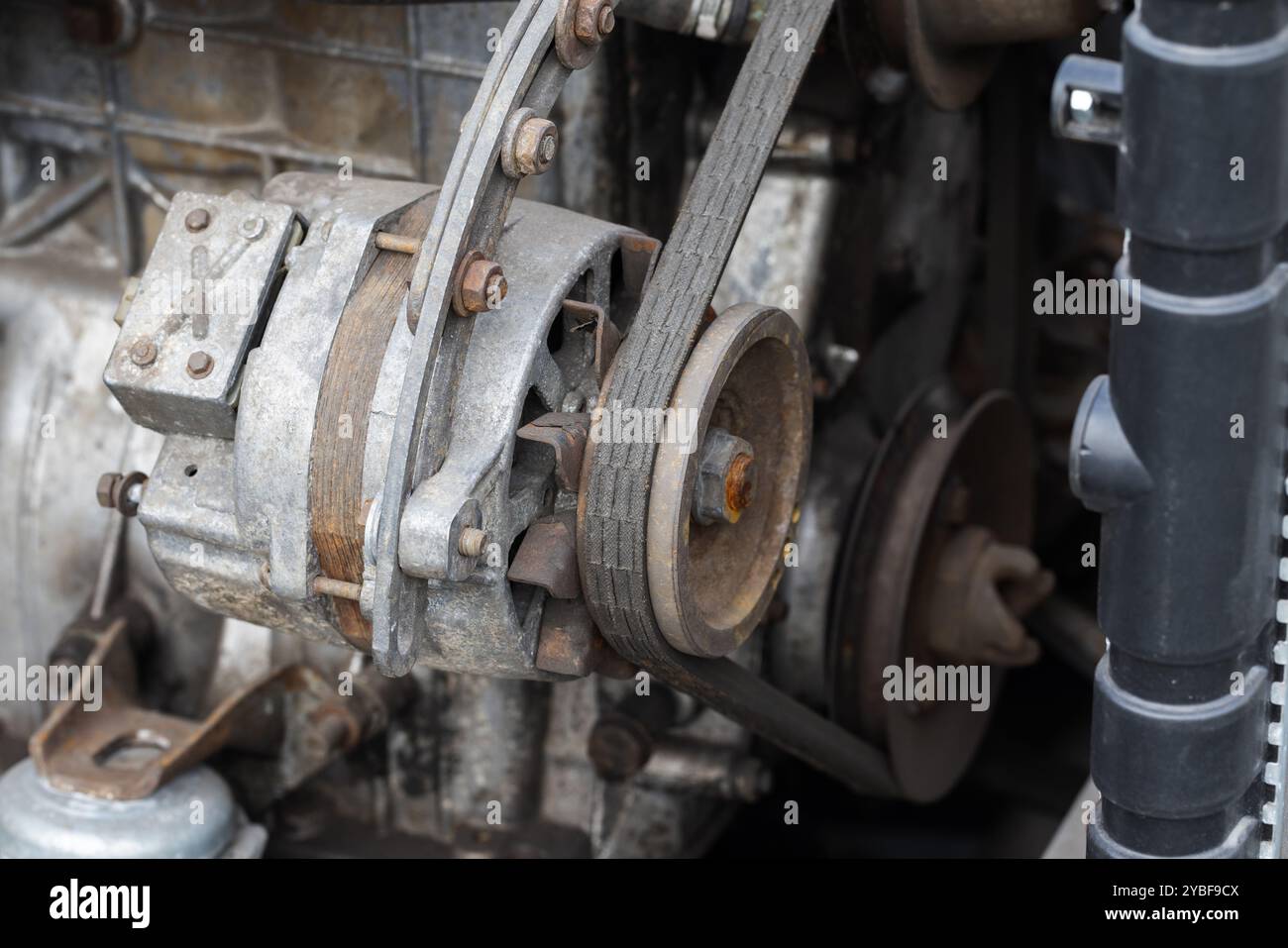 Old car engine parts, close-up photo of used dynamo with timing belt ...