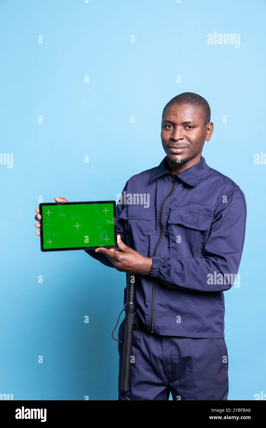 Confident security officer in uniform holds a device with chromakey ...