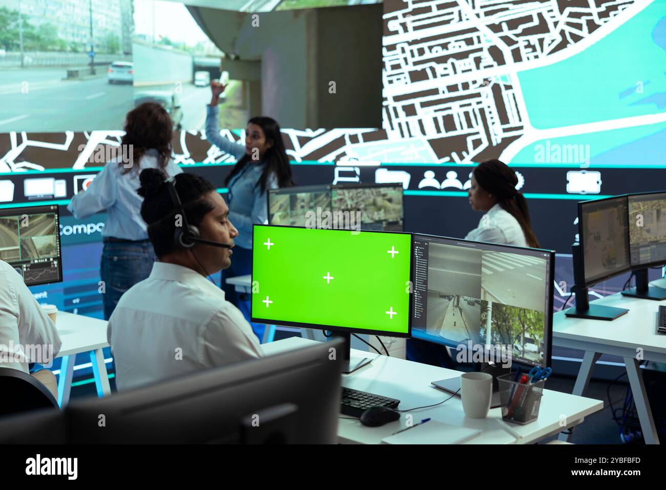 Indian male dispatcher uses isolated mockup screen next to CCTV footage ...