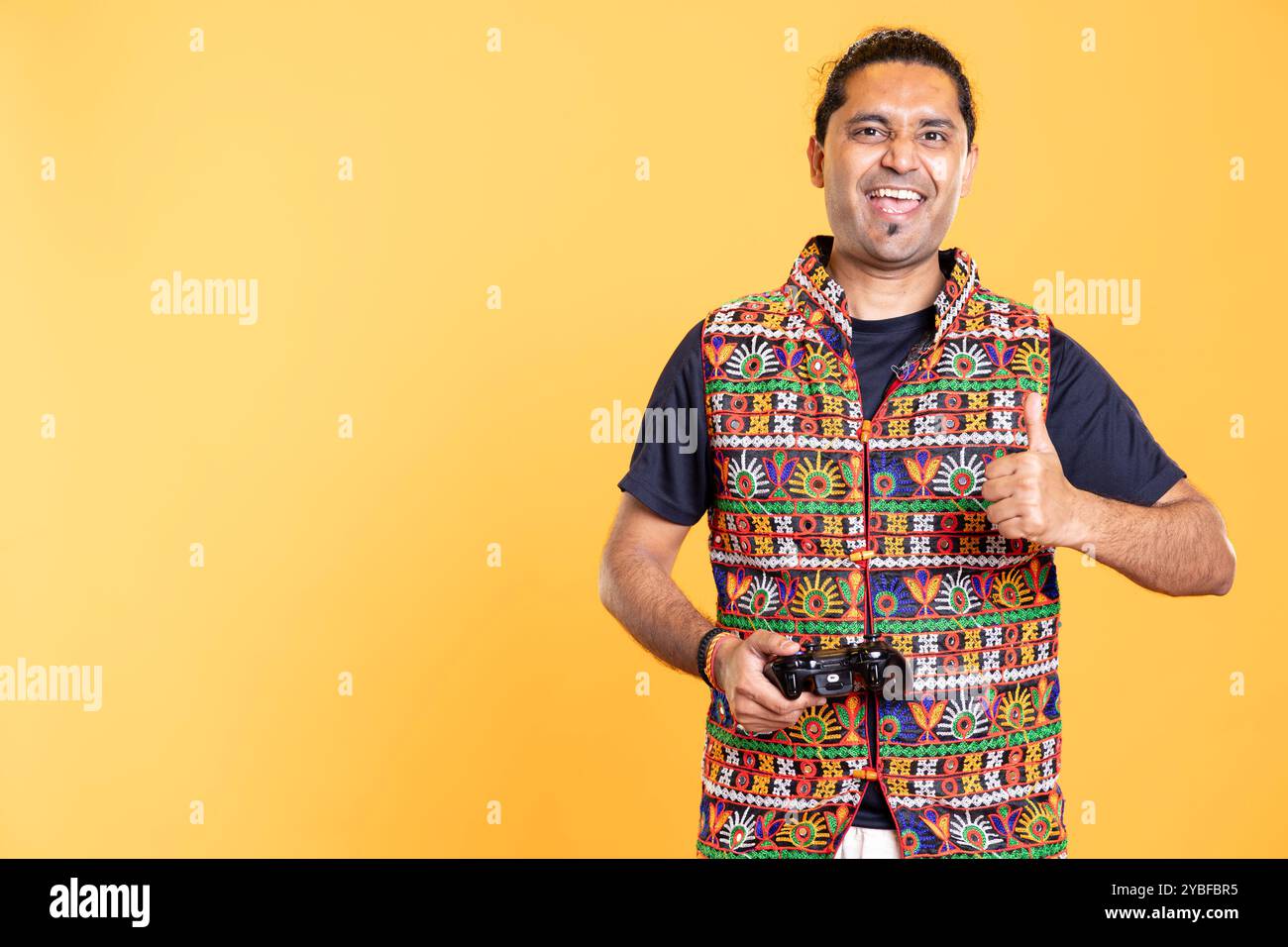 Cheerful gamer showing thumbs up sign gesturing holding controller ...