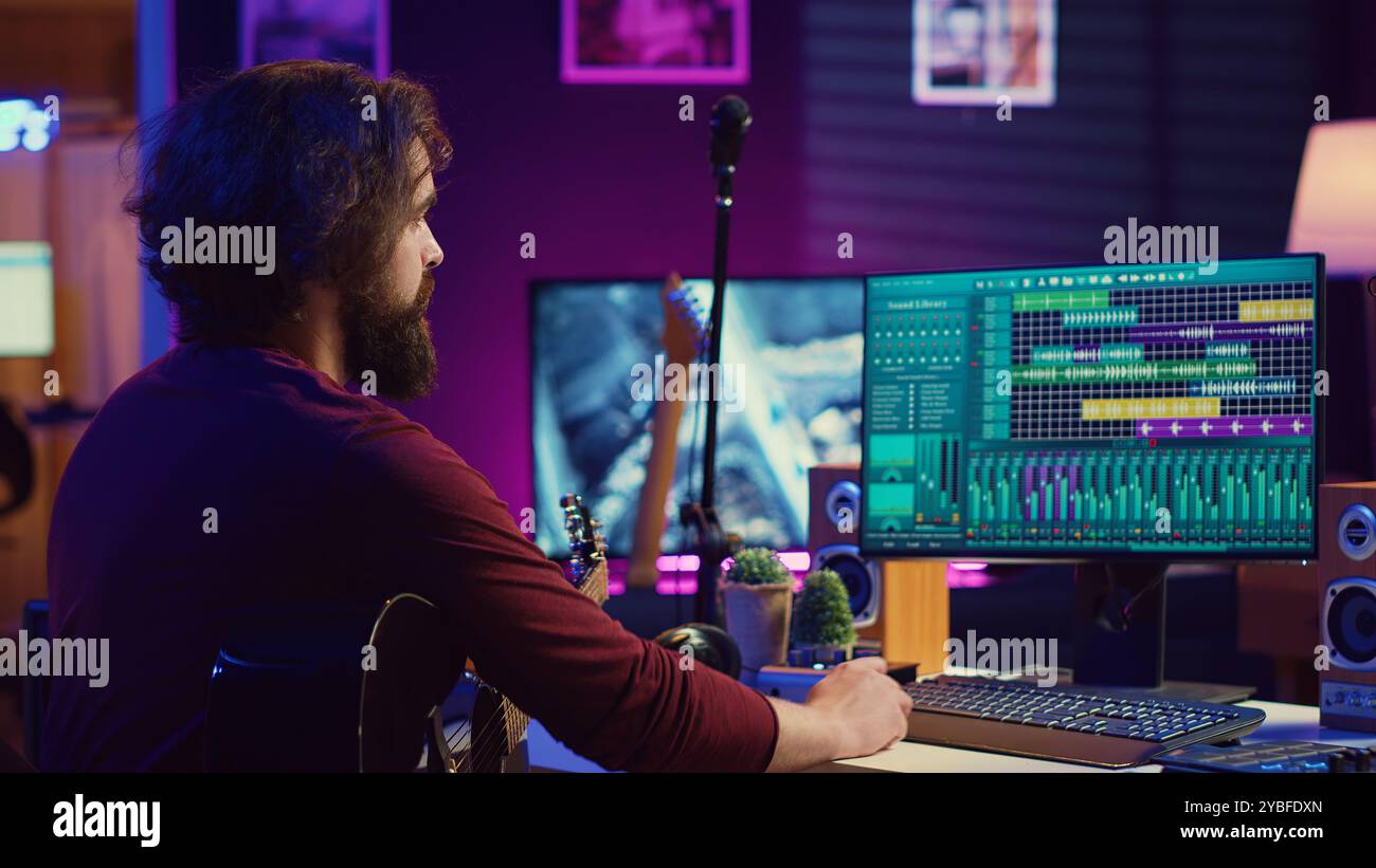 Music producer operating with electronic setup of home studio ...