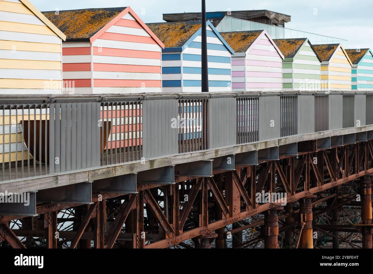Brightly painted beach huts create a vibrant display along a wooden ...