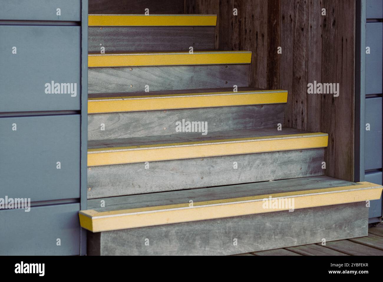 A staircase constructed from gray wood features bold yellow strips on ...