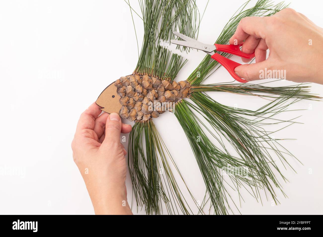 DIY fish craft cutting with red scissors, pine cones, pine needles. Top ...