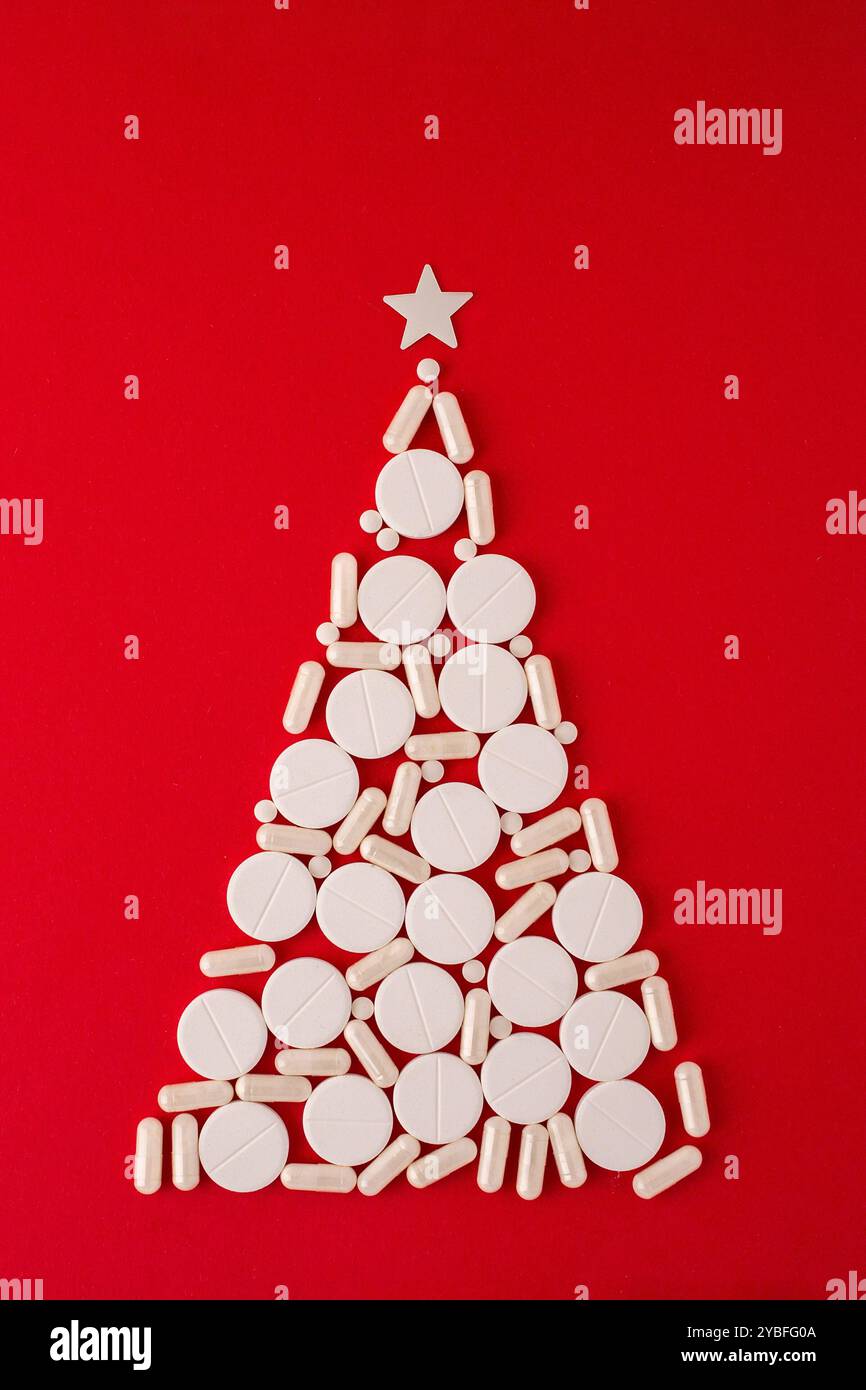 White tablets forming Christmas tree shape, red background, star tablet ...