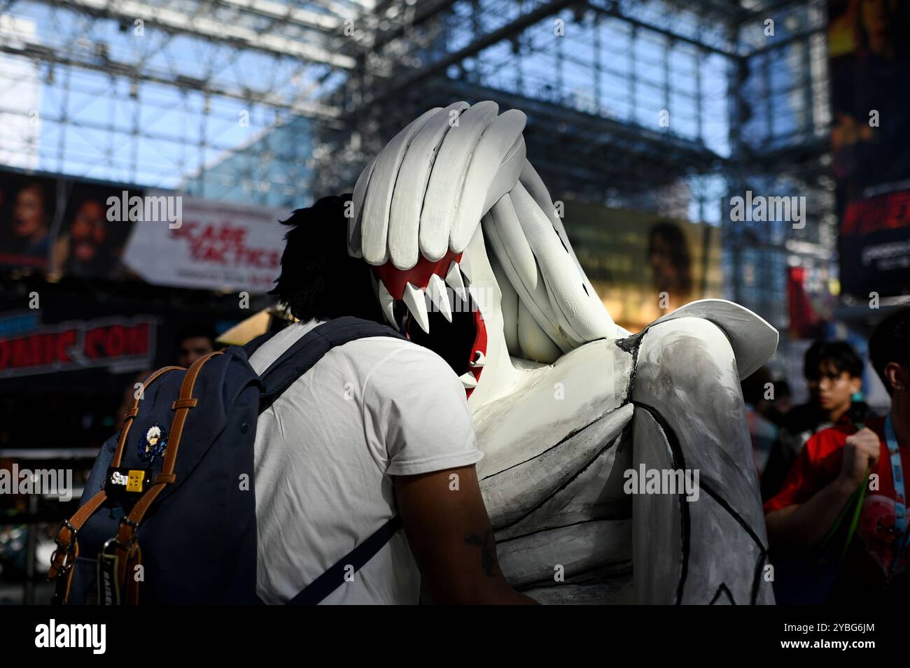 A man carries a hand-crafted monster costume through crowds during the ...