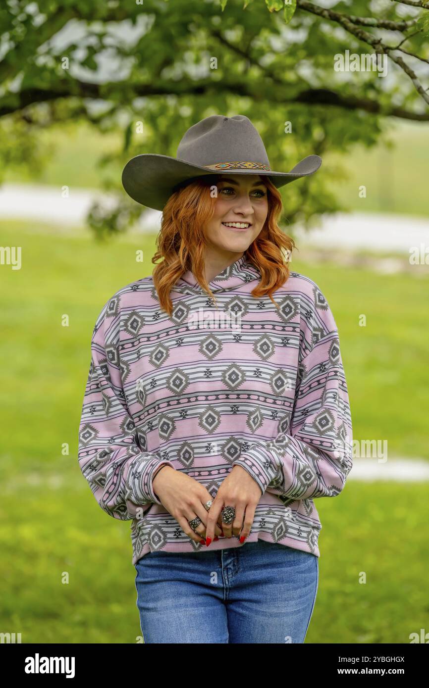 A beautiful redhead model poses in a country setting wearing cowgirl ...