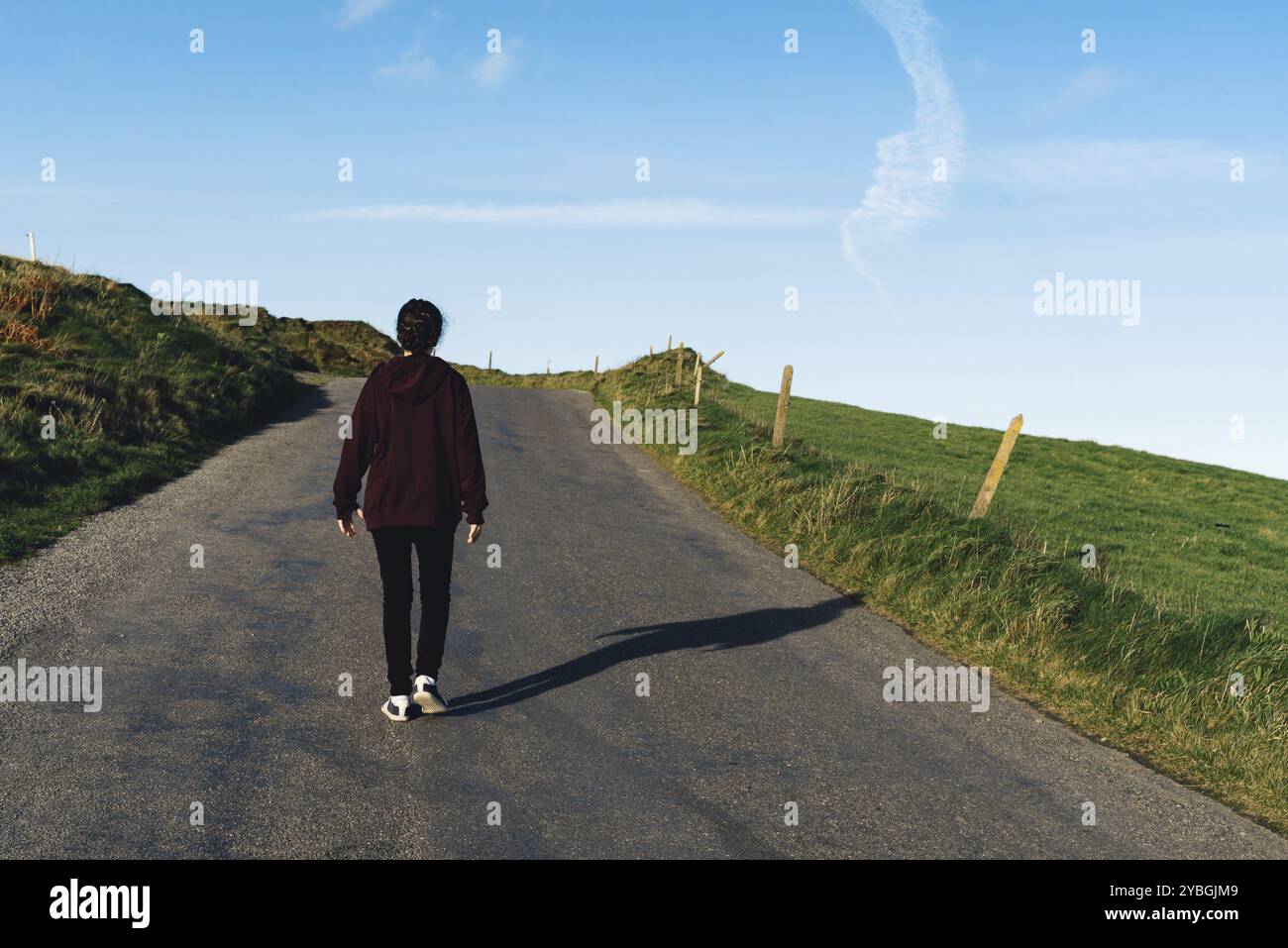 Young woman walking on lonely road next to green fields Stock Photo - Alamy