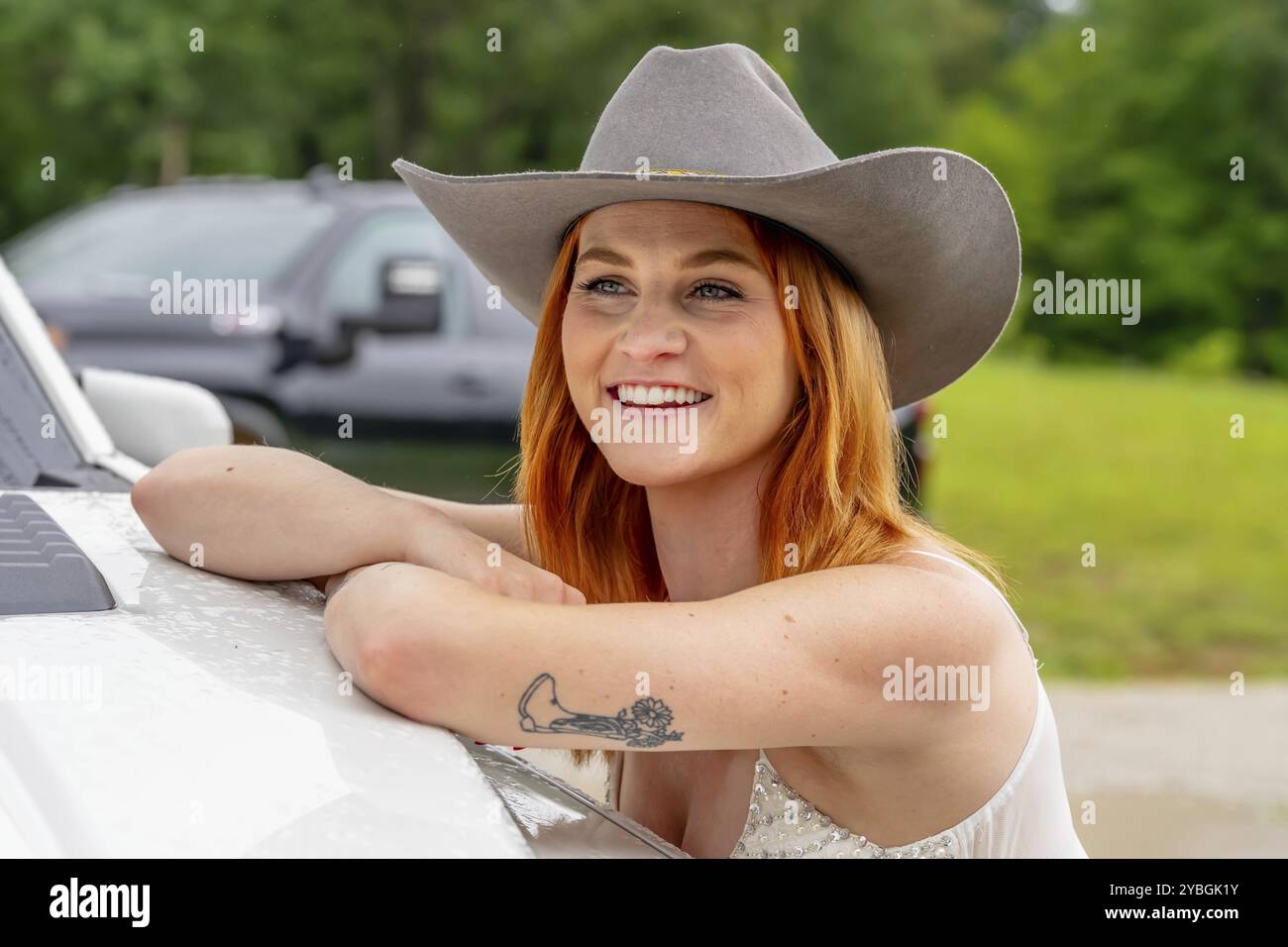 A Beautiful Redhead Model Poses In A Country Setting Wearing Cowgirl