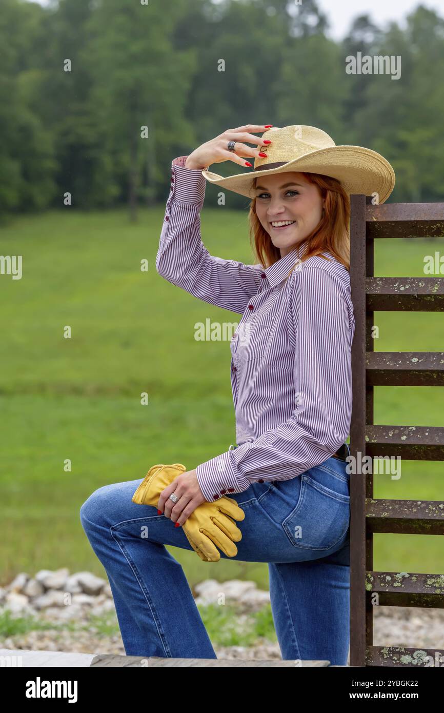 A beautiful redhead model poses in a country setting wearing cowgirl ...