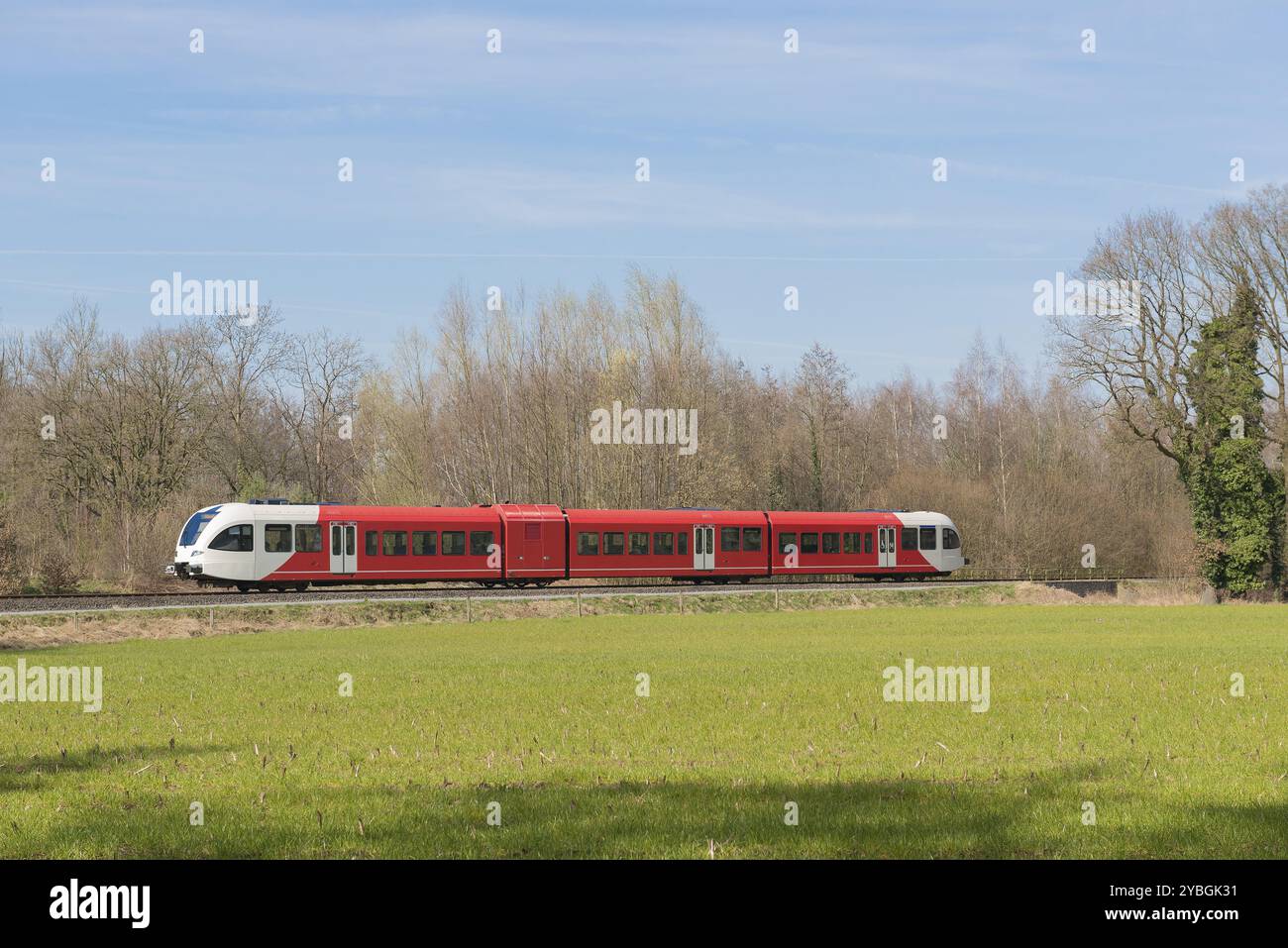 Red white colored train on a light rail track in the Achterhoek near ...