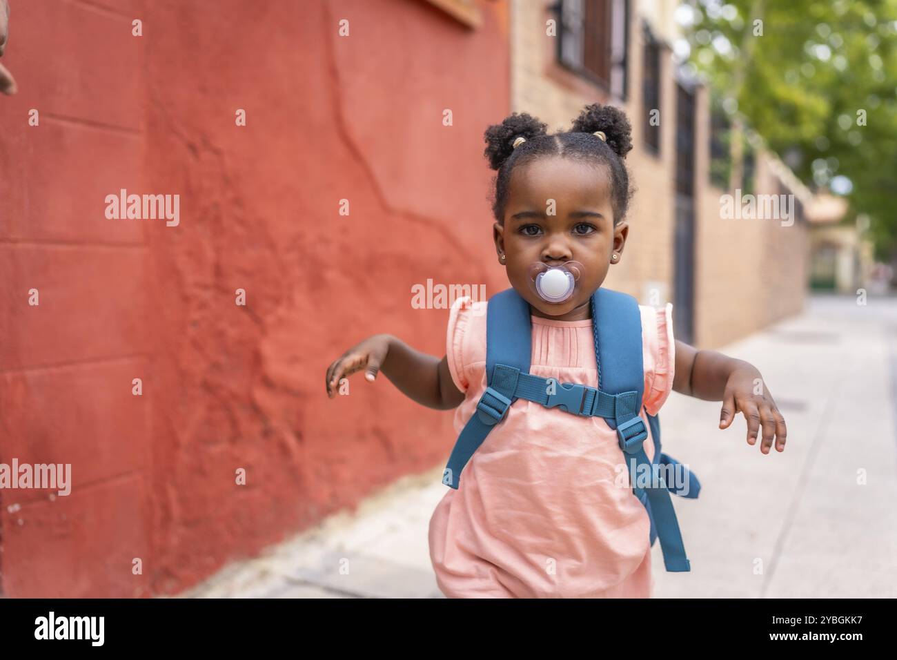 Cute baby african girl running along a street using pacifier Stock ...