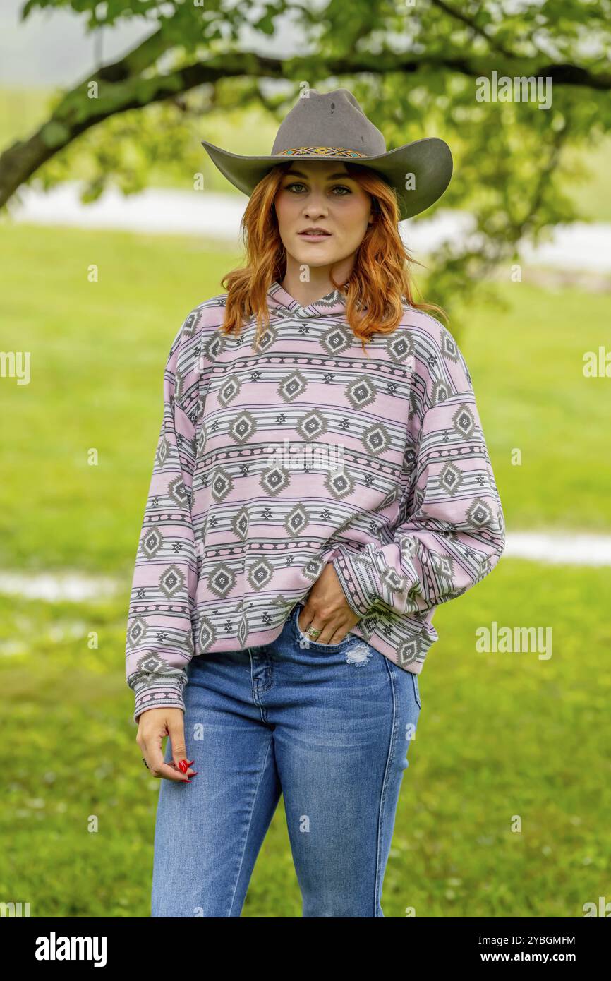 A beautiful redhead model poses in a country setting wearing cowgirl ...