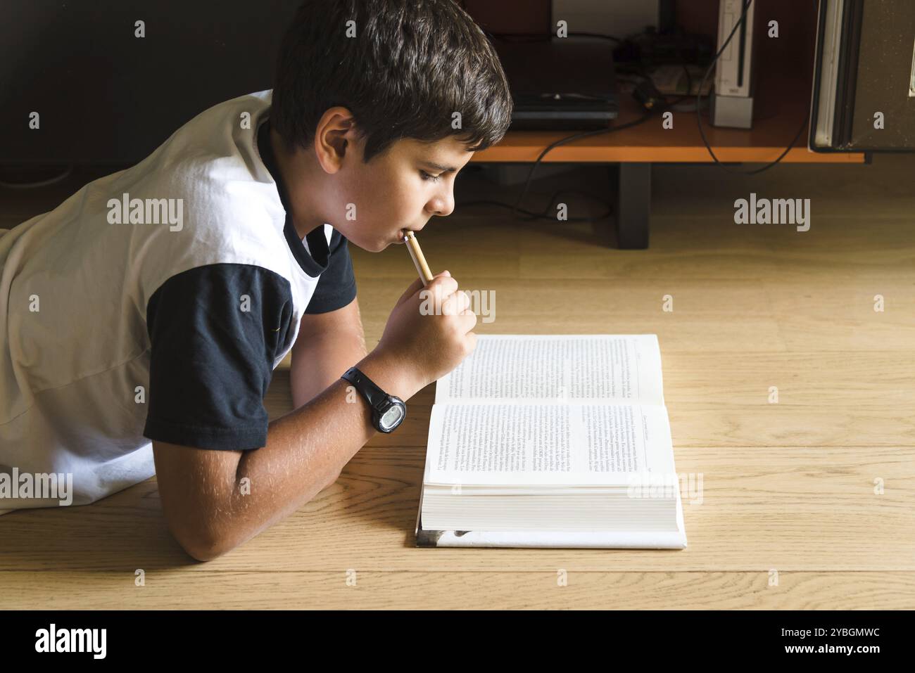 Little boy child reading a book. He lies on the floor. Side view ...