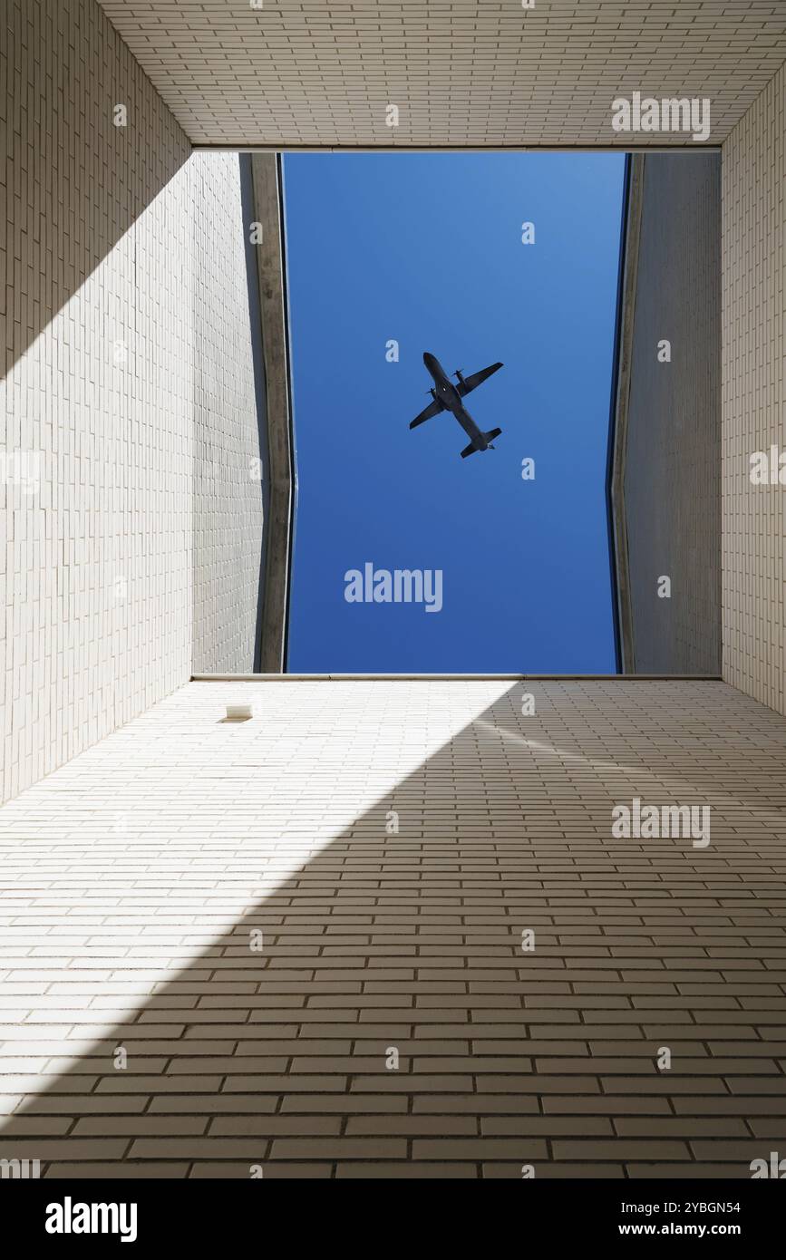 Plane flying above courtyard of modern architecture brick building ...