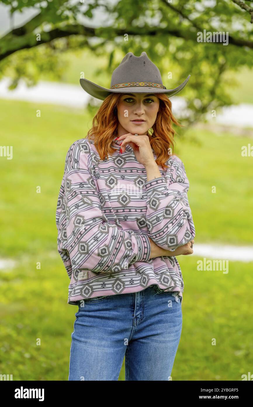 A beautiful redhead model poses in a country setting wearing cowgirl ...