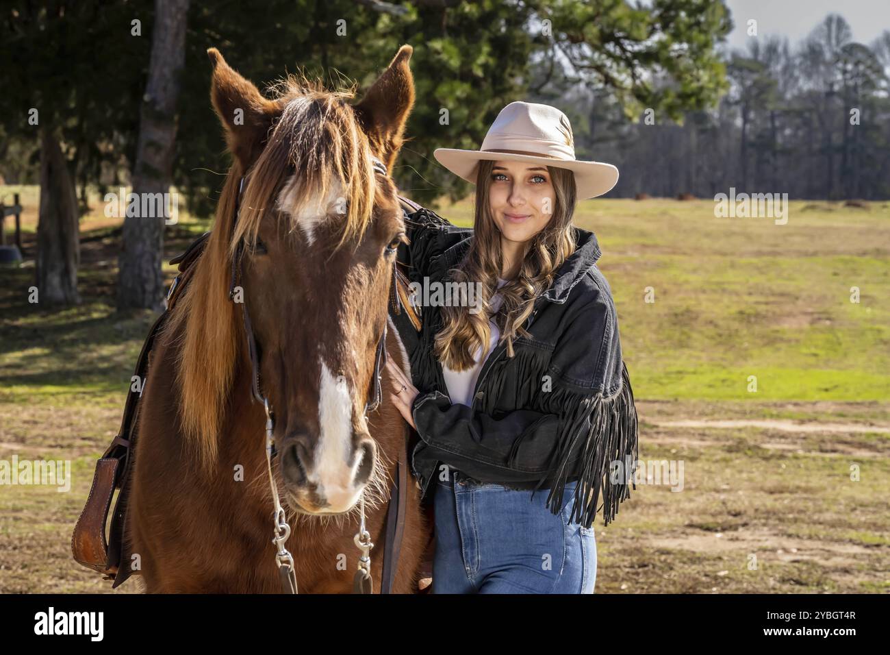 A beautiful brunette cowgirl poses with her horse before a ride in the countryside Stock Photo ...