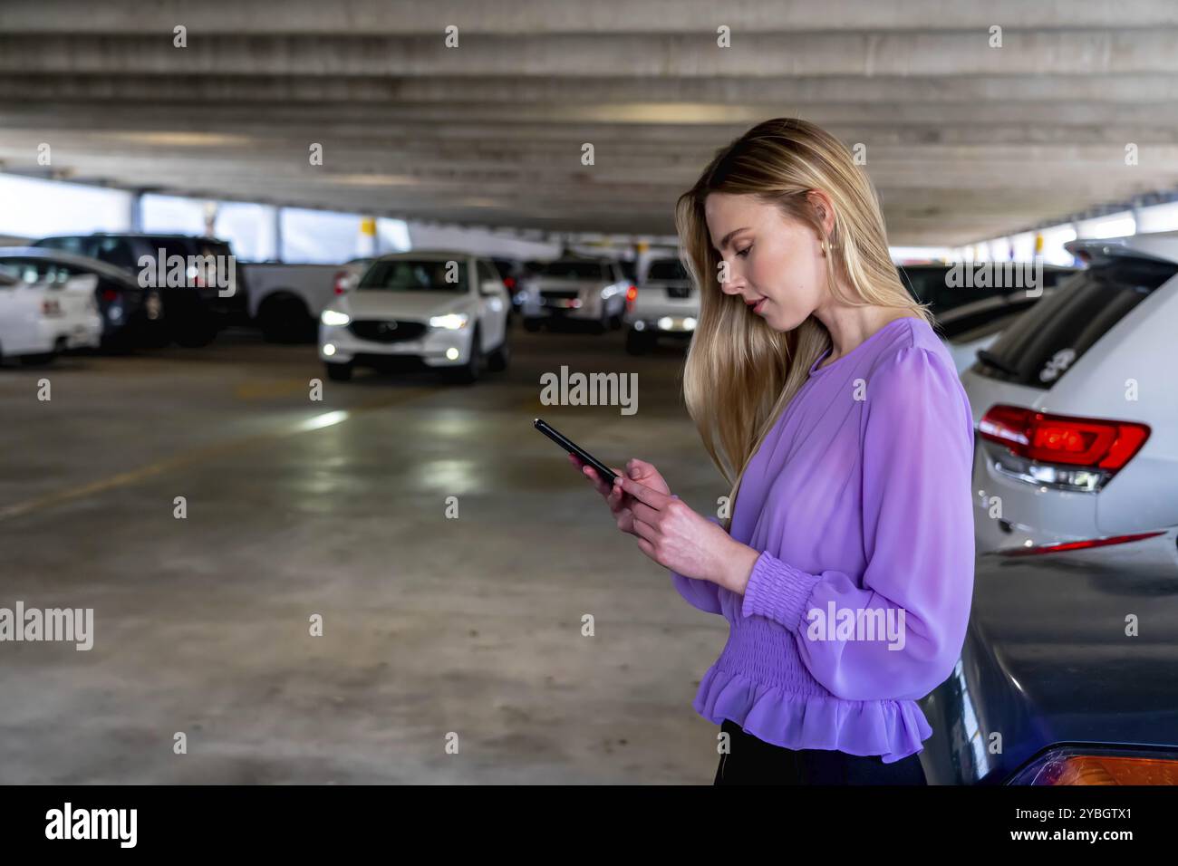 A gorgeous blonde model walks to her car in a covered parking garage after a successful meeting ...