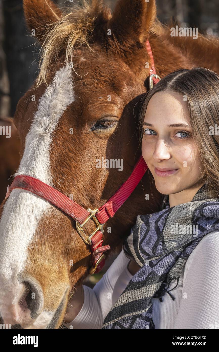A beautiful brunette cowgirl poses with her horse before a ride in the ...