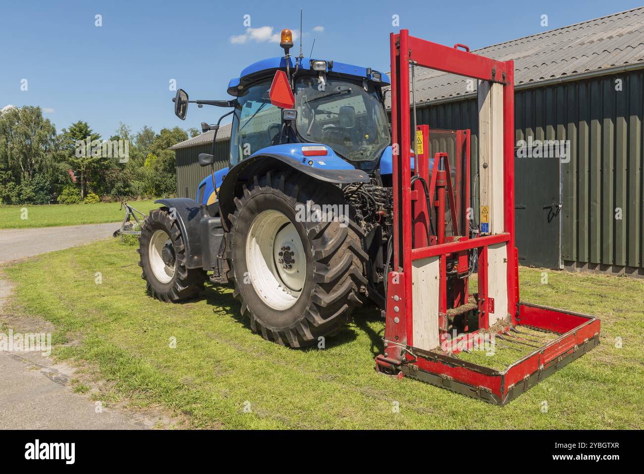 Blue tractor with a red bale slicer for cutting off silage bales Stock ...