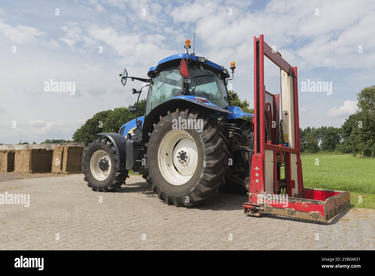 Blue tractor with a red bale slicer for cutting off silage bales Stock ...