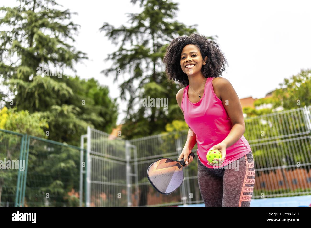 Portrait of happy latin female pickleball player about to serve at ...