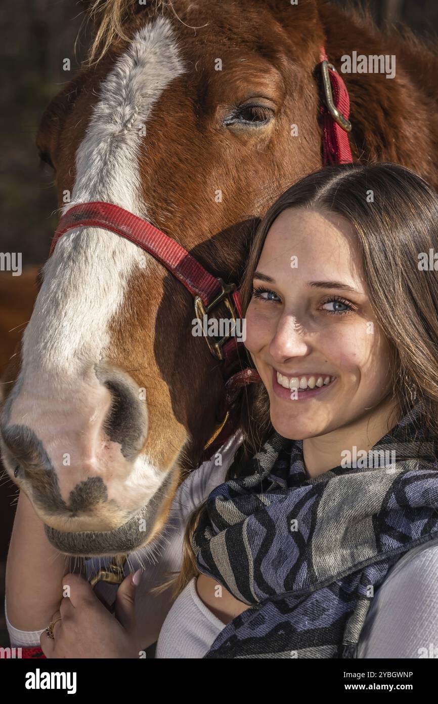A beautiful brunette cowgirl poses with her horse before a ride in the ...