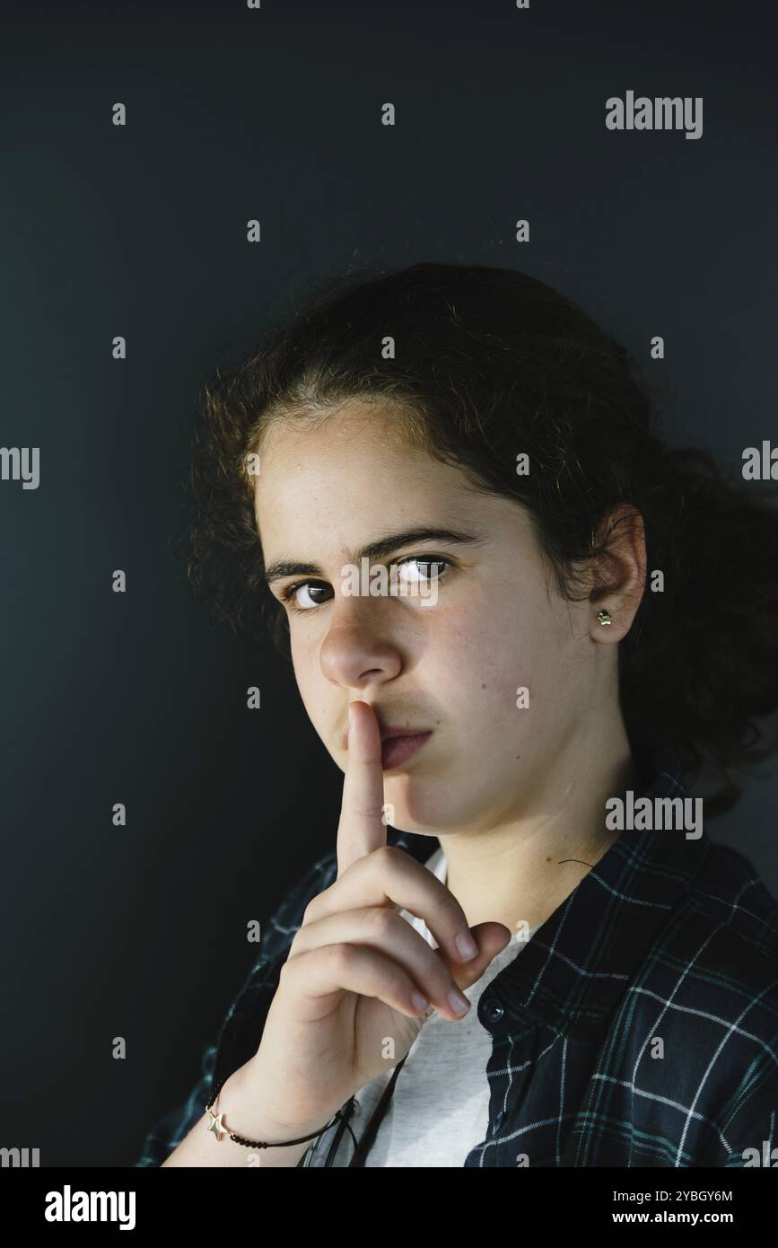 Headshot portrait of defiant teenager with finger on lips making ...