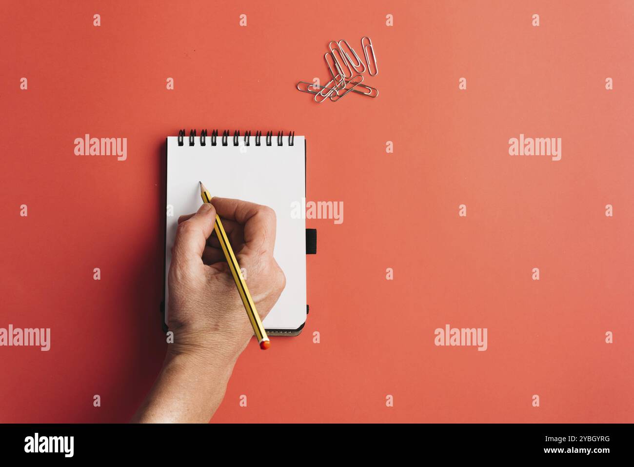Lay flat of woman hand with pencil writing on blank page of notebook ...