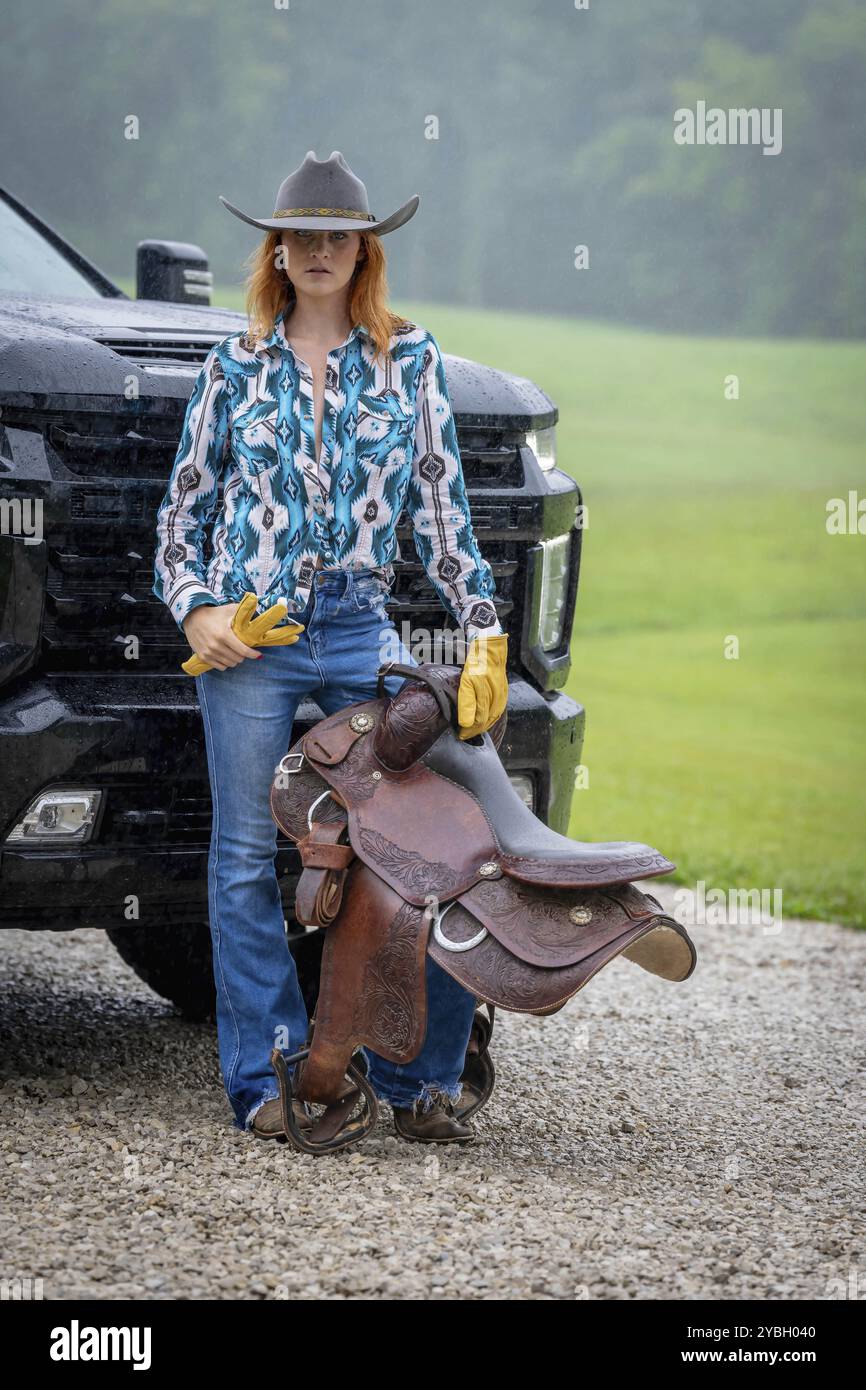 A beautiful redhead model poses in a country setting wearing cowgirl ...
