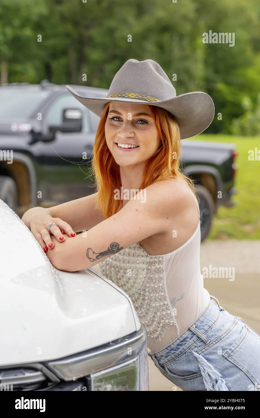 A beautiful redhead model poses in a country setting wearing cowgirl ...