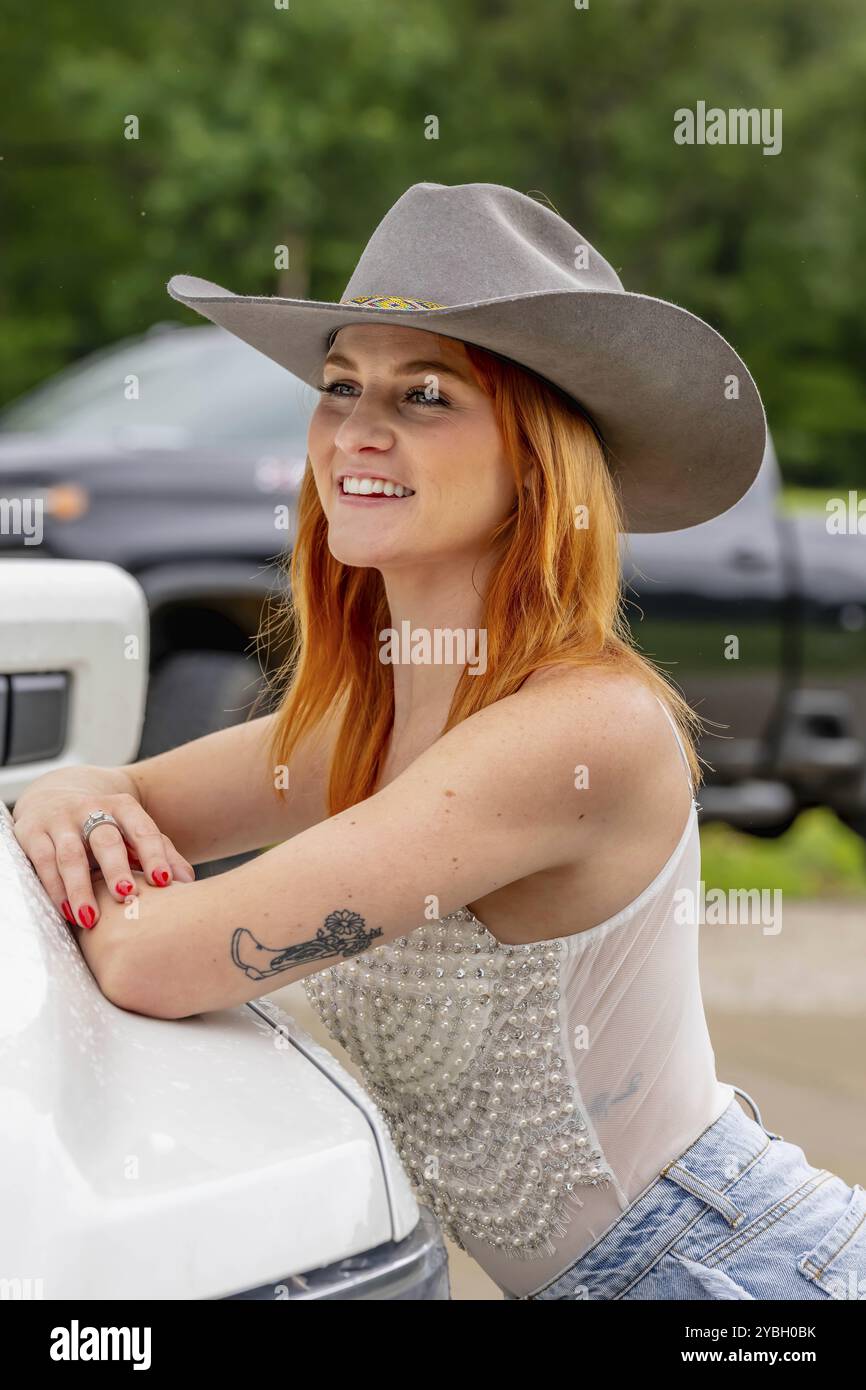 A beautiful redhead model poses in a country setting wearing cowgirl ...