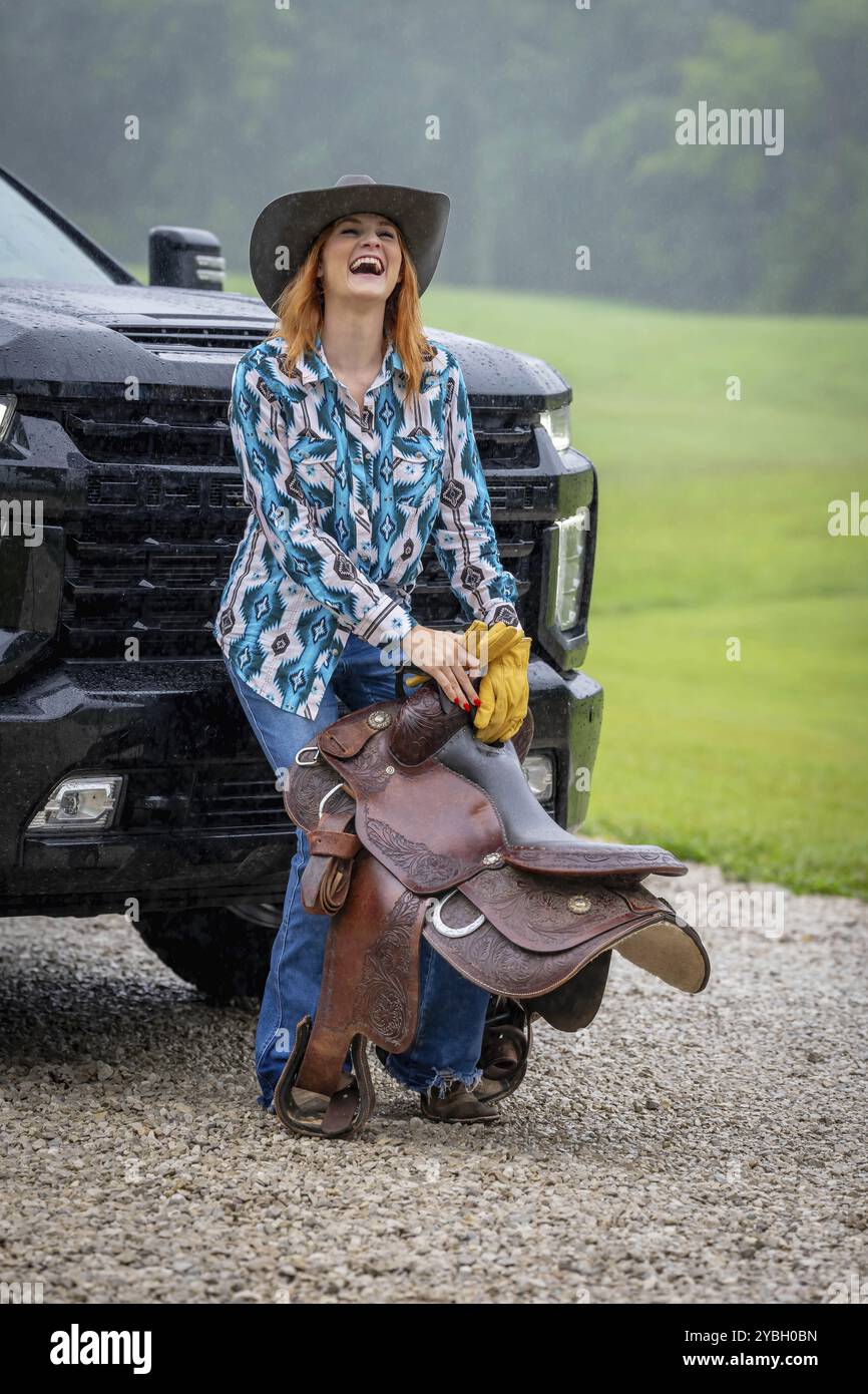 A beautiful redhead model poses in a country setting wearing cowgirl ...