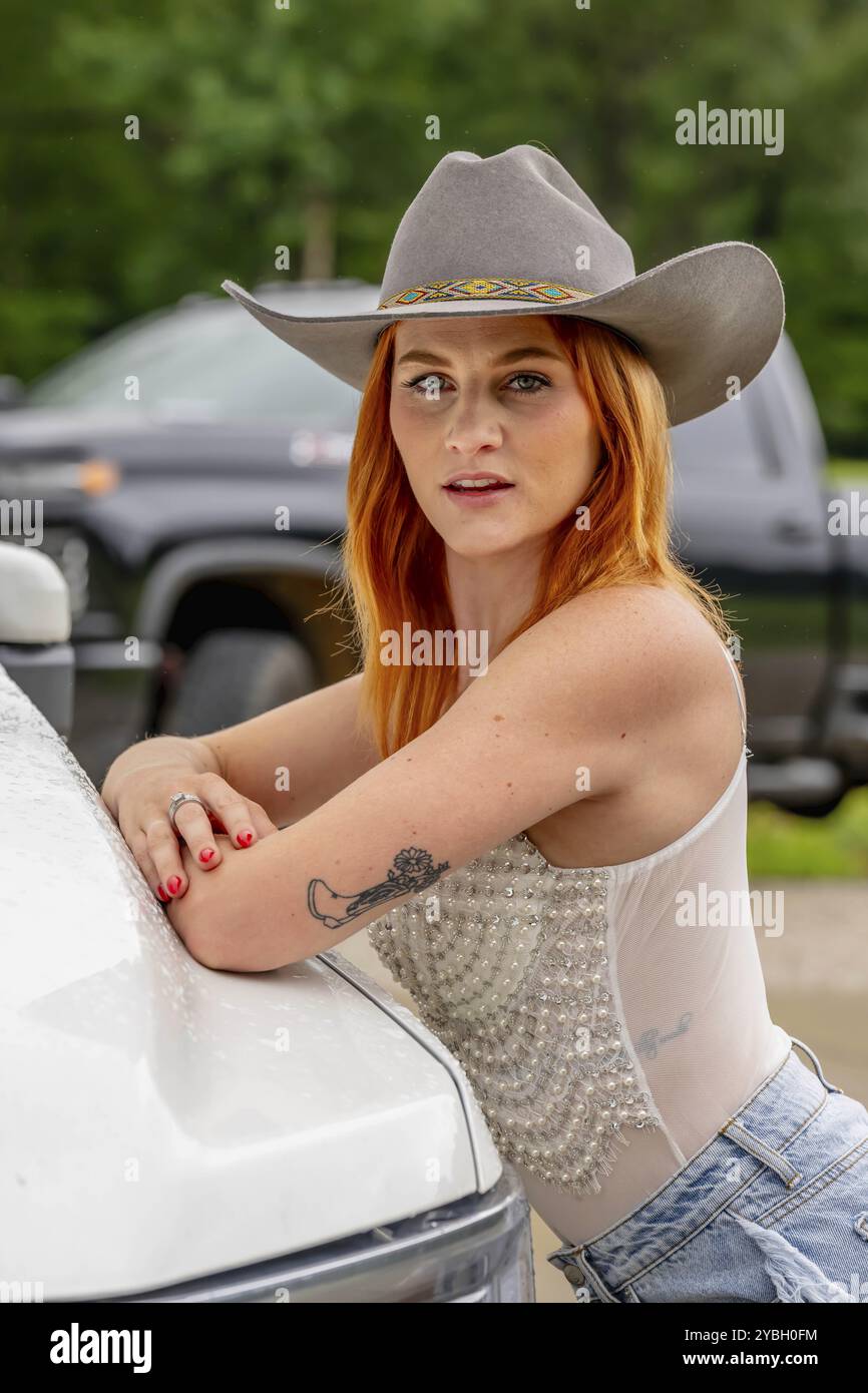 A Beautiful Redhead Model Poses In A Country Setting Wearing Cowgirl