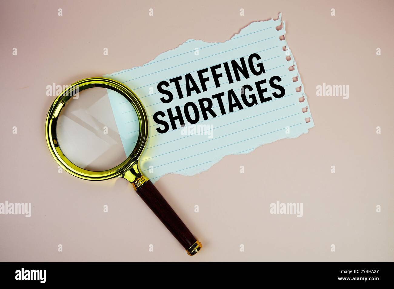 Staffing Shortages text written on paper torn top view on pink ...