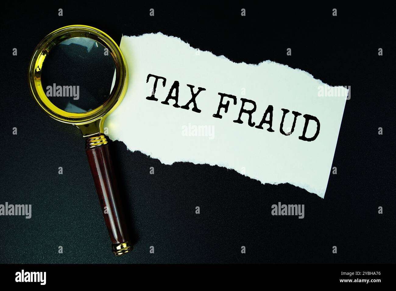 Tax Fraud text on paper torn with magnifying glass top view on black ...