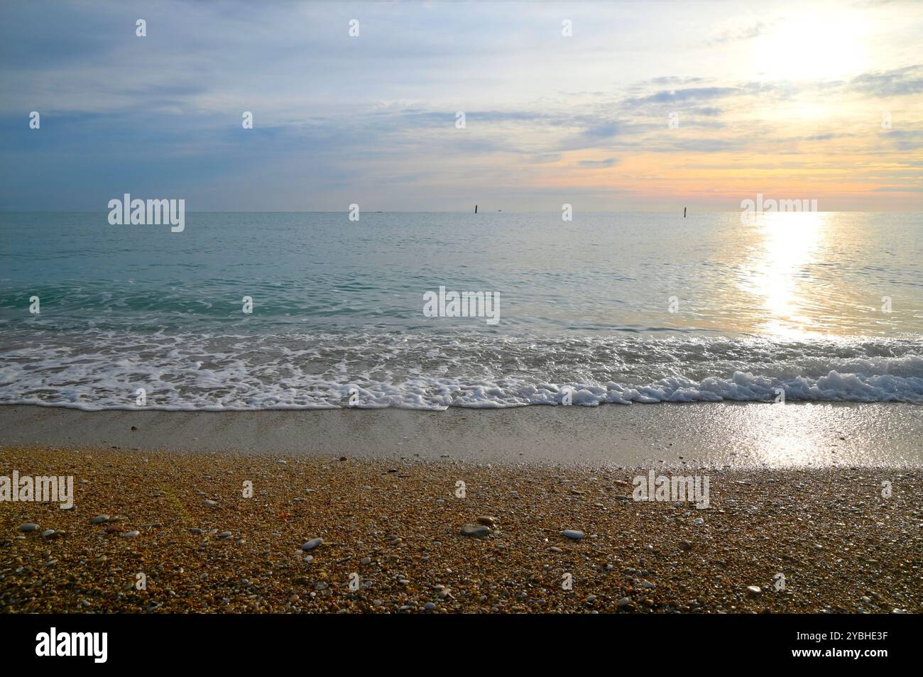 Calm sea in the morning with waves that fade on a beach of small stones ...