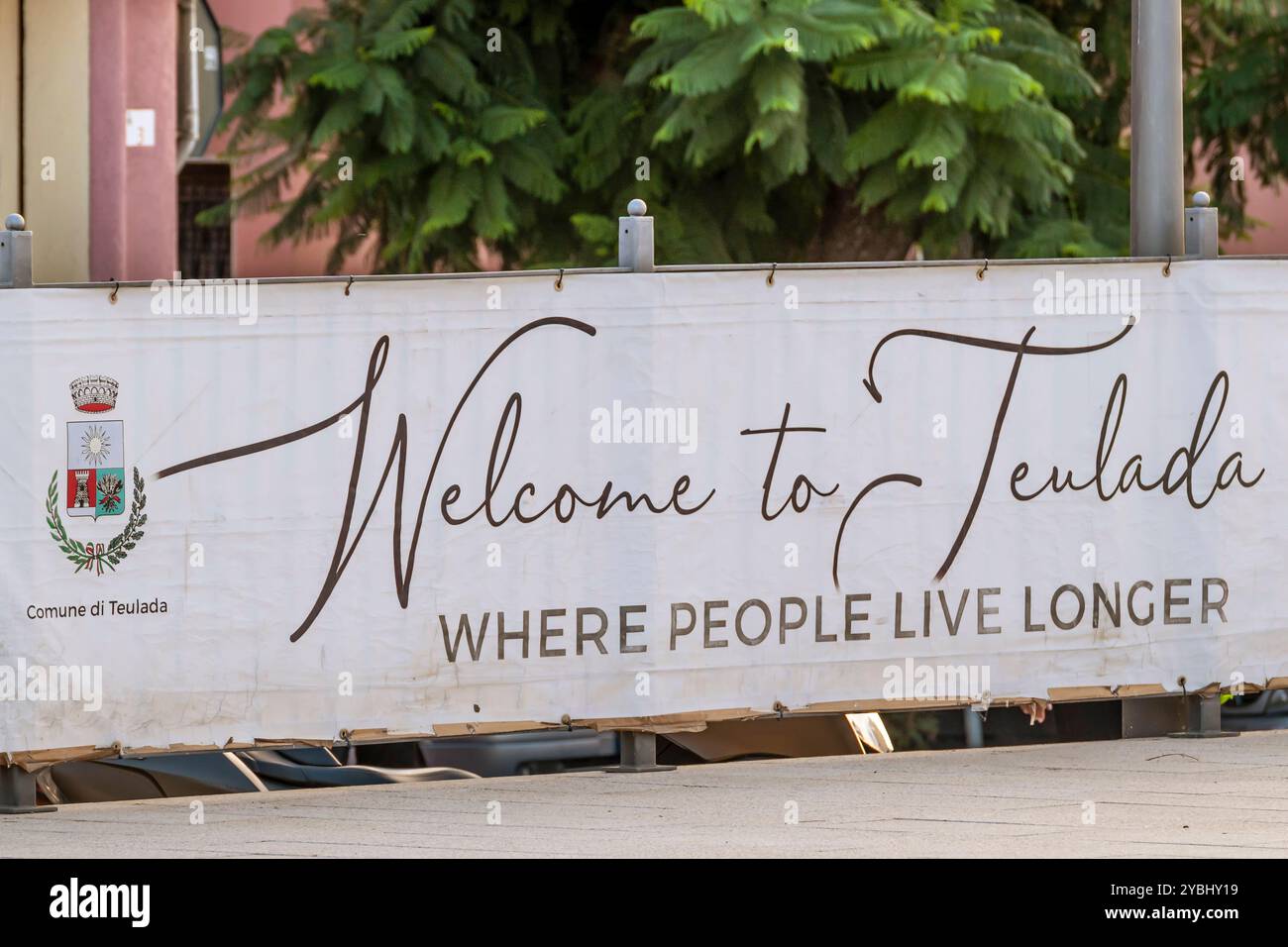 A banner welcomes visitors to Teulada, Sardinia, Italy, where people ...