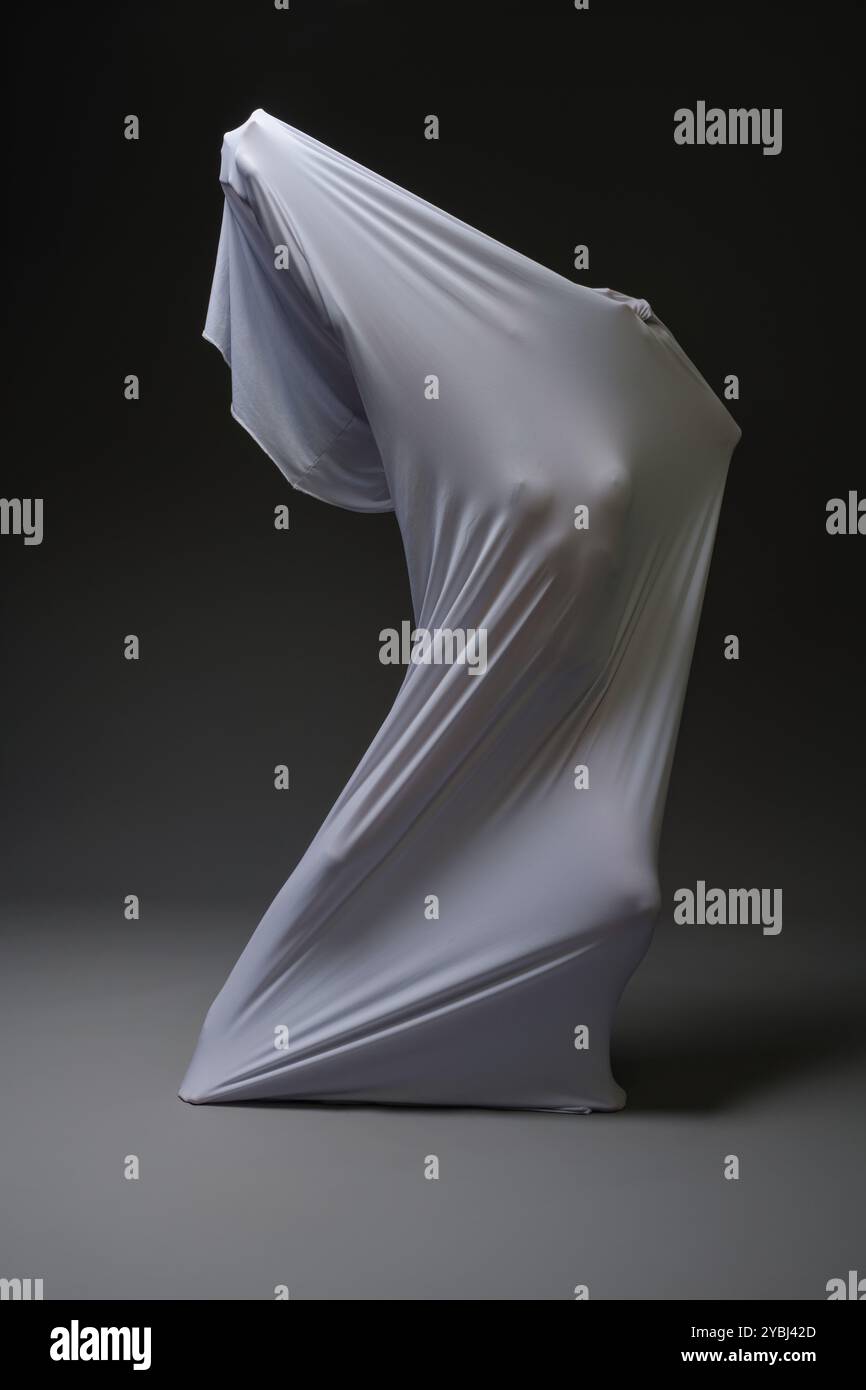 Draped figure forms a bold silhouette on a dark background Stock Photo ...