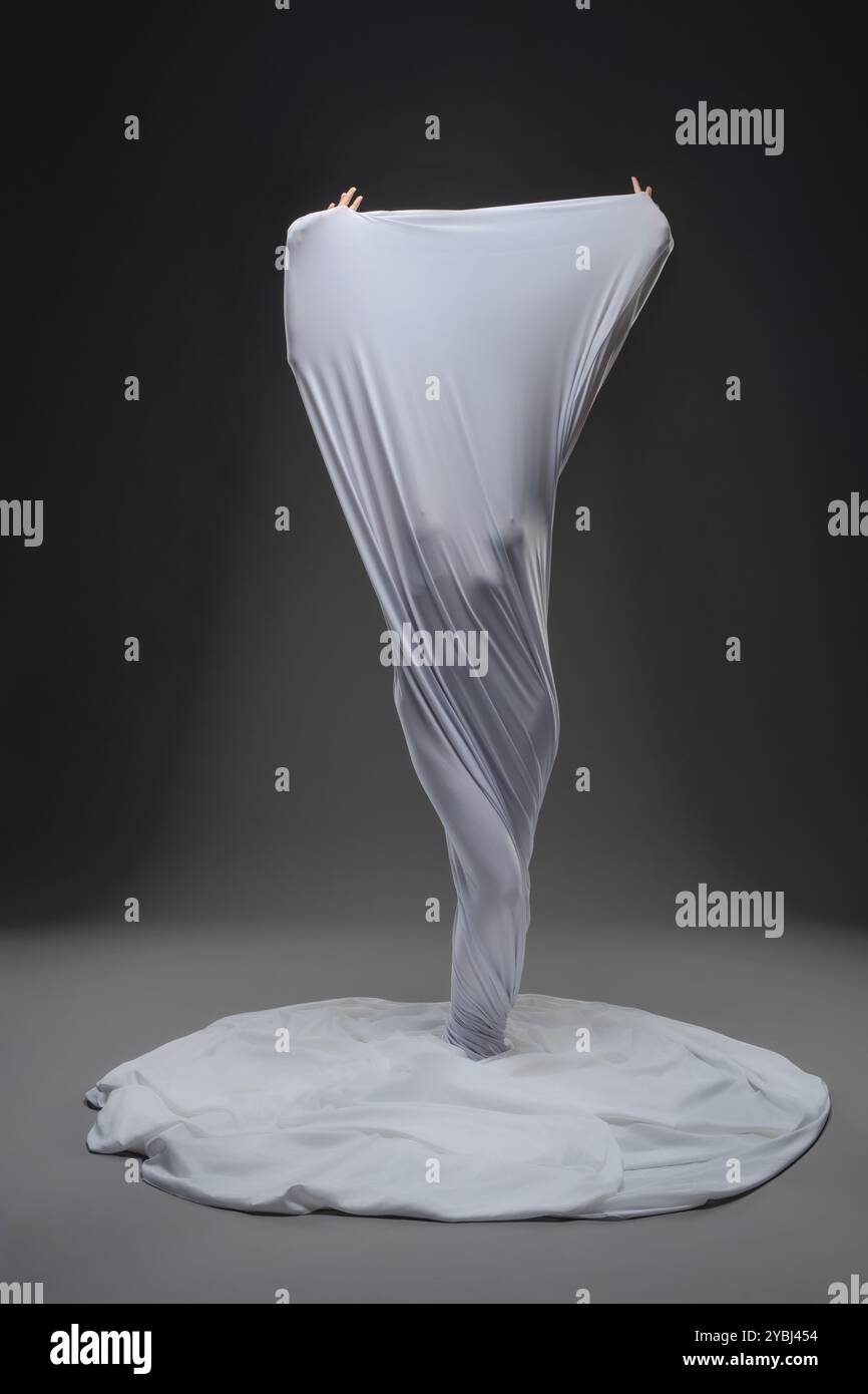 A dynamic figure emerging from a white fabric whirlwind in a dark ...