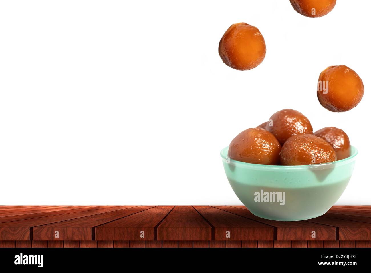 Traditional Indian sweet gulab jamun falling into green bowl on wooden ...