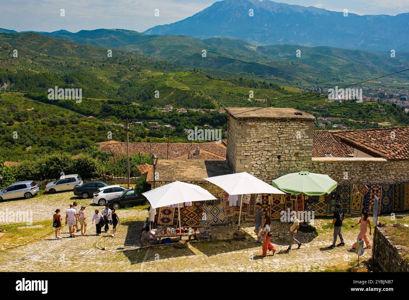 Berat, Albania - June 2nd 2024. Visitors walk past rugs, clothes and ...